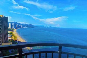 Paisagem costeira com praia, edifícios altos e céu claro.