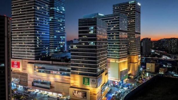 Paisagem urbana com edifícios altos, ruas movimentadas e letreiros iluminados.