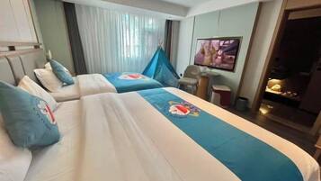 Quarto de hotel com duas camas, televisão, escrivaninha e janela com cortinas.