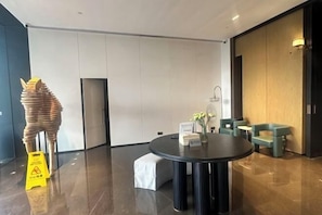 Um hall de hotel moderno com uma mesa redonda, área de estar e uma escultura de madeira única.