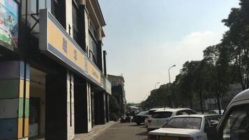 Rua com carros estacionados e um edifício com uma placa.