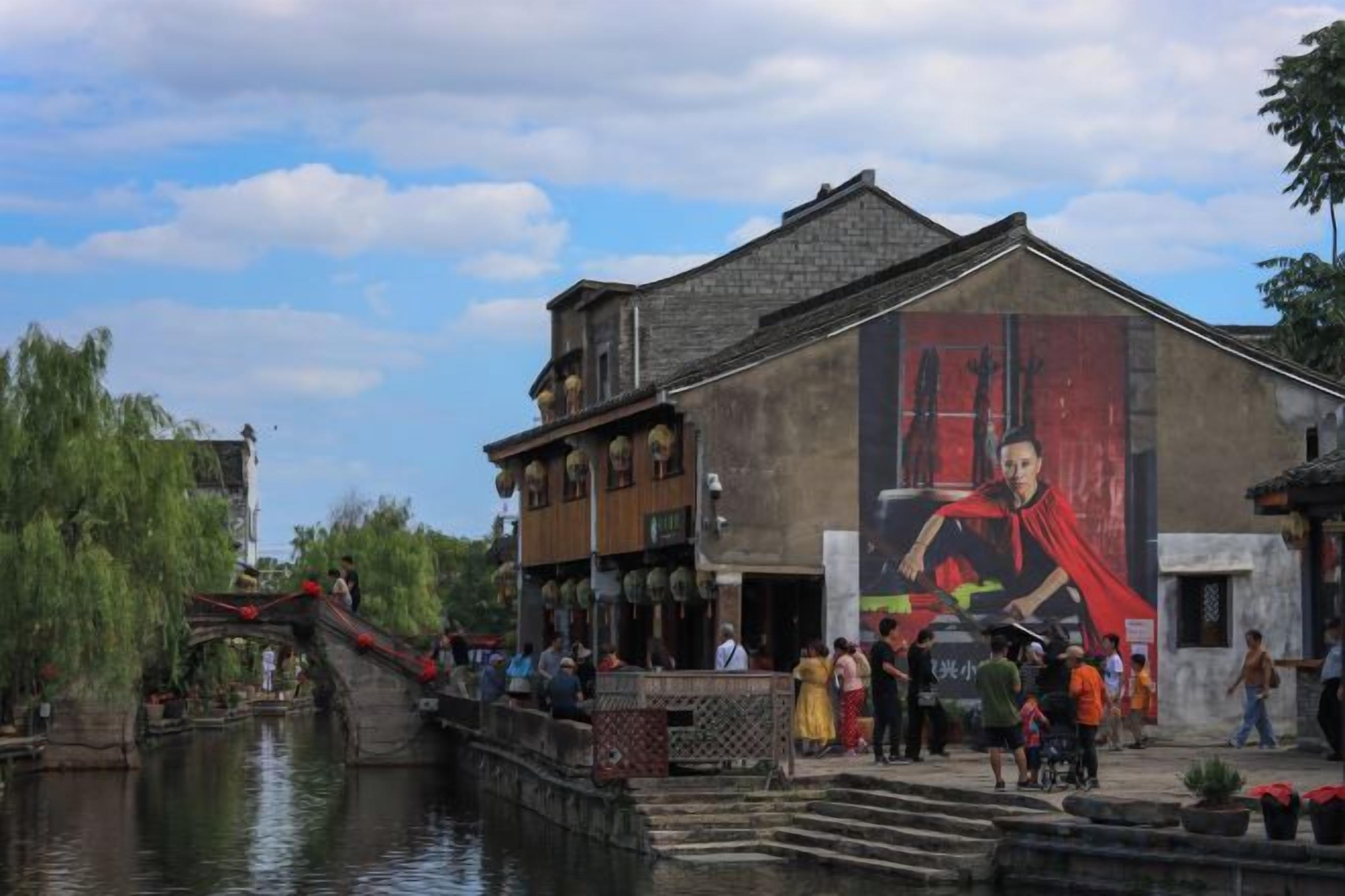 Um edifício tradicional com um mural, um canal e uma ponte.
