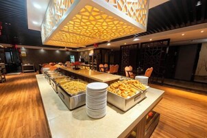 Disposição de buffet com diversas estações de comida e organização de mesas.