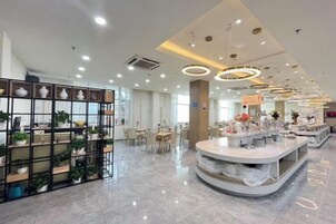 Um hall de hotel moderno, com balcão de recepção, área de estar e plantas decorativas.