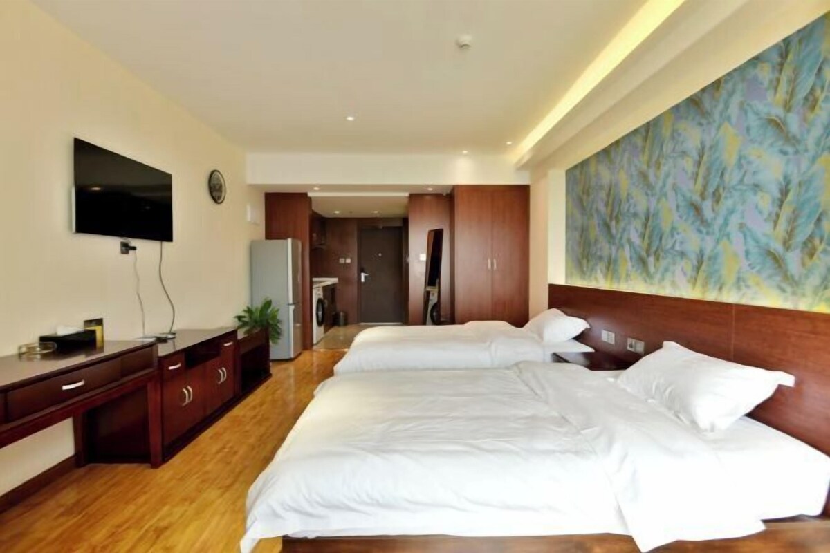 Quarto de hotel com uma cama grande, uma escrivaninha, uma TV de tela plana e um quadro na parede.