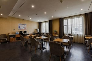 Quarto de hotel com área de jantar, cozinha compacta e uma janela grande com cortinas.