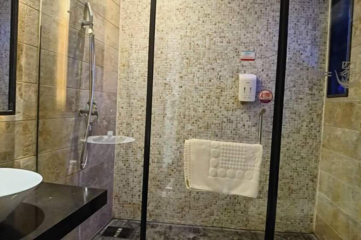 Casa de banho com cabine de chuveiro em vidro, porta-toalhas e lavatório.