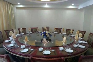 Sala de conferência com uma mesa redonda, cadeiras e um arranjo floral central.