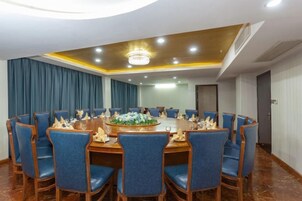 Sala de conferência com mesa redonda, cadeiras azuis e um candelabro.