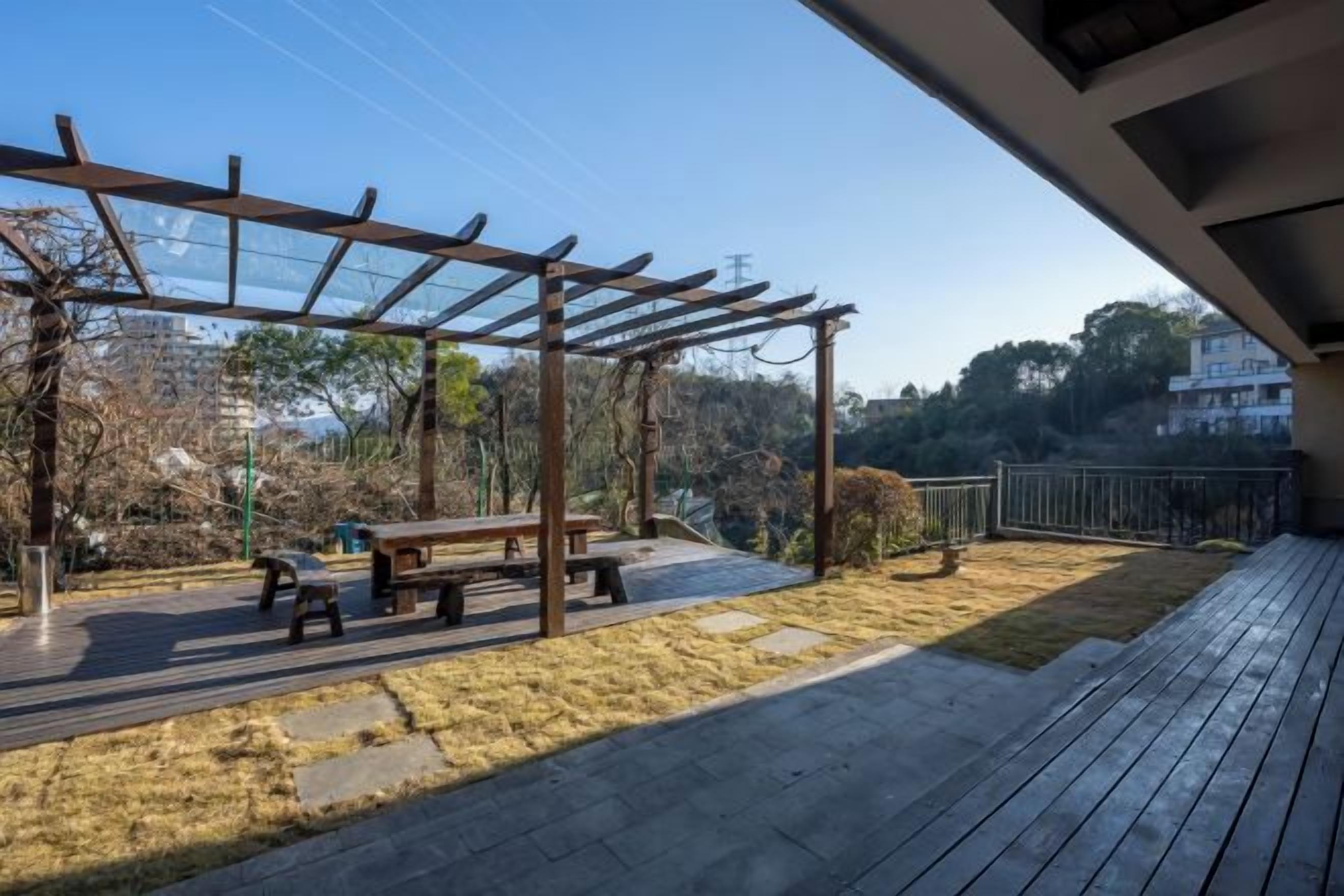 Um pátio externo com pérgola, assentos e vista para a paisagem ao redor.