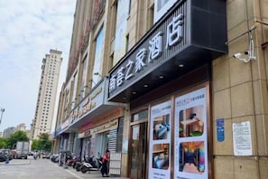 Um edifício com uma placa indicando 'Nanjing Hotel' e várias lojas no andar térreo.