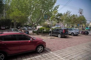 Uma área de estacionamento com vários carros, árvores e céu claro.