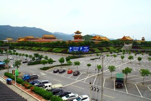 Um estacionamento com vários carros e um edifício grande com arquitetura tradicional ao fundo.