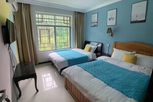 Quarto de hotel com duas camas, televisão, janela com cortinas e quadros na parede.