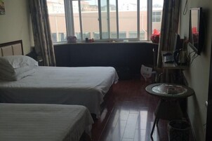 Quarto de hotel com duas camas, uma mesa pequena e uma janela com vista para edifícios.