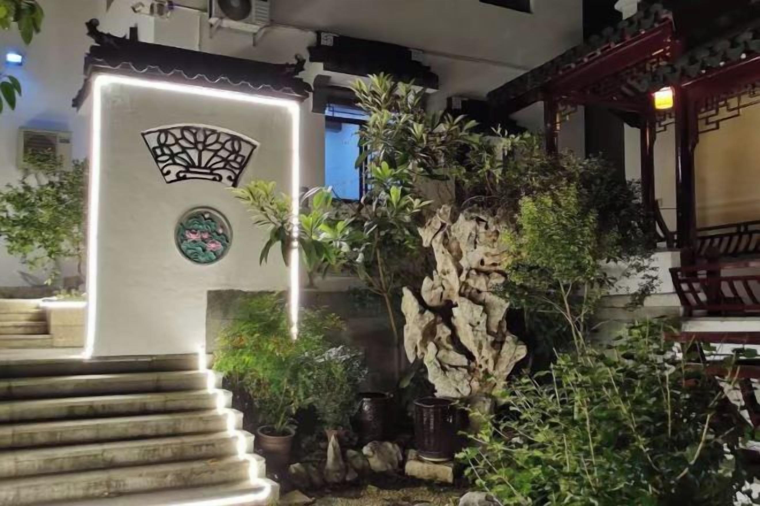 Um pátio tradicional com escadaria de pedra, formação rochosa e plantas em vasos.