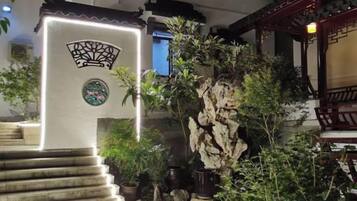 Um pátio tradicional com escadaria de pedra, formação rochosa e plantas em vasos.