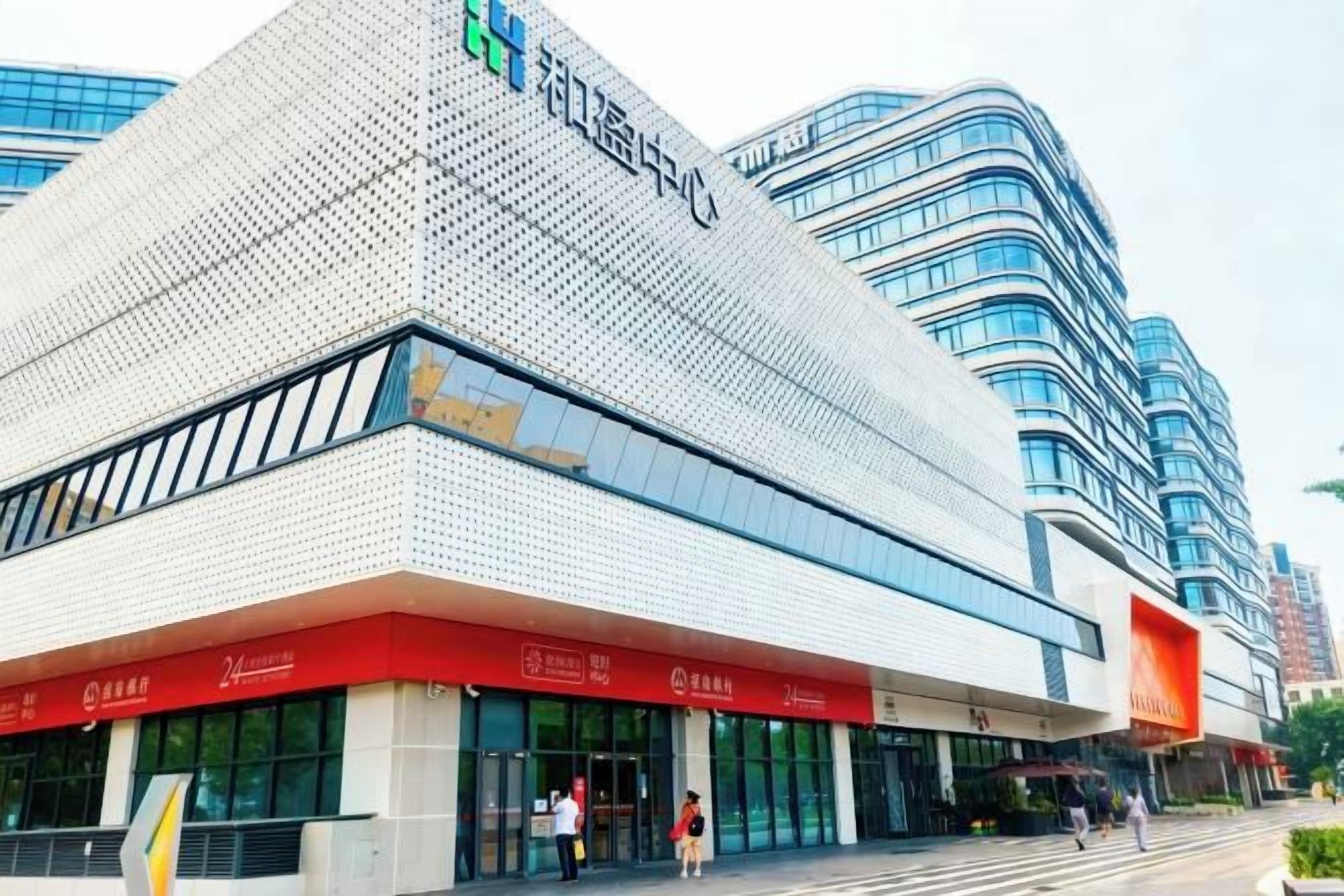 Um edifício moderno com fachada geométrica marcante, grandes janelas e entrada imponente.
