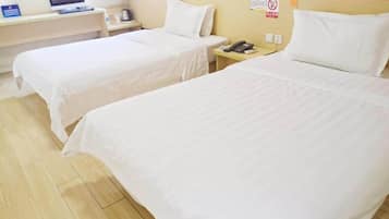Quarto de hotel com duas camas, uma mesa com computador, telefone e uma placa na parede.