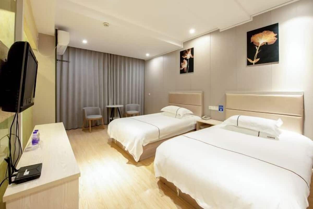 Quarto de hotel com duas camas, uma escrivaninha, uma televisão e uma pequena mesa.