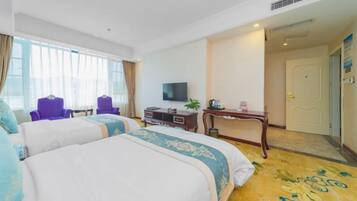 Quarto de hotel com duas camas, televisão, escrivaninha e porta.