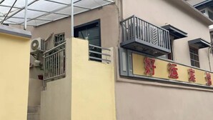 Um edifício com fachada amarela e varanda com grades de metal.