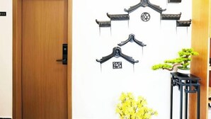 Quarto com porta de madeira, um objeto decorativo preto fixado na parede e uma pequena planta em vaso.