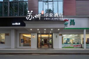 Entrada de hotel com uma placa que diz 'JIMAGE HOTEL' e uma fachada com uma placa verde.