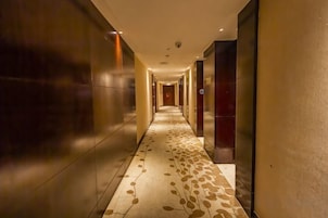 Corredor comprido e estreito com carpete estampado e luminárias modernas.