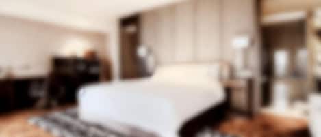 Quarto de hotel com uma cama, mesa de cabeceira e abajur.