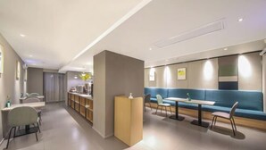 Restaurante moderno com balcão extenso, área de estar com bancos acolchoados em azul e um pequeno posto de recepção.