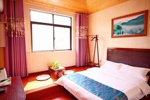 Quarto com cama, janela, quadro e uma pequena mesa com uma planta.