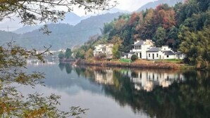 Um cenário tranquilo à beira do lago, com arquitetura tradicional, águas calmas e vegetação exuberante ao redor.