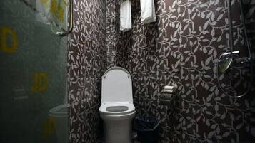 Casa de banho com sanita, chuveiro e parede estampada.