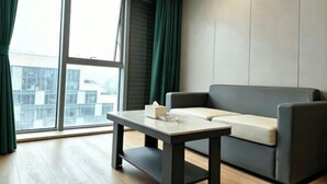 Uma sala de estar moderna com um sofá, uma mesinha e uma janela grande com cortinas.