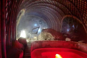 Uma estrutura em forma de túnel com área de estar acolchoada em vermelho e um pequeno palco com microfone.