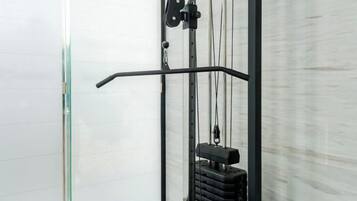 Academia equipada com aparelhos de ginástica, incluindo barra de tração e pilha de pesos.