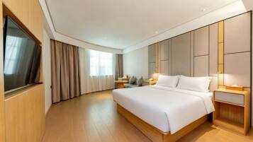 Quarto de hotel moderno com uma cama grande, mesas de cabeceira, uma TV e uma janela com cortinas.