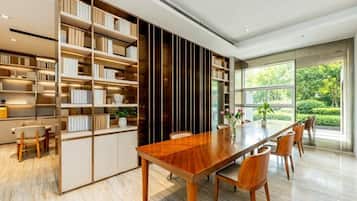 Uma sala de jantar moderna com uma longa mesa de madeira, cadeiras e uma estante embutida.