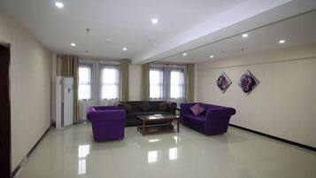 Uma sala de estar ampla com um conjunto de sofás, uma mesa de centro e duas poltronas roxas.