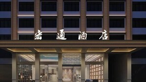 Entrada de hotel com letreiros iluminados e fachada moderna.