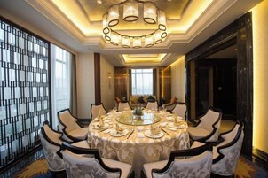 Uma sala de jantar formal com uma mesa redonda, cadeiras e um lustre.