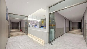 Um hall de hotel moderno com balcão de recepção, portas de vidro e piso de mármore.