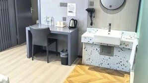 Um quarto pequeno com escrivaninha, cadeira e pia.
