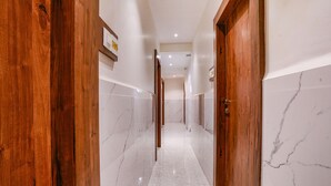 Corredor com portas de madeira e paredes de mármore branco.