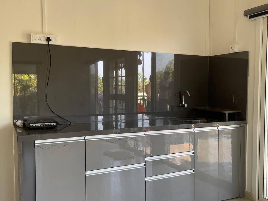 Uma cozinha com bancada preta, armários de aço inoxidável e forno embutido.