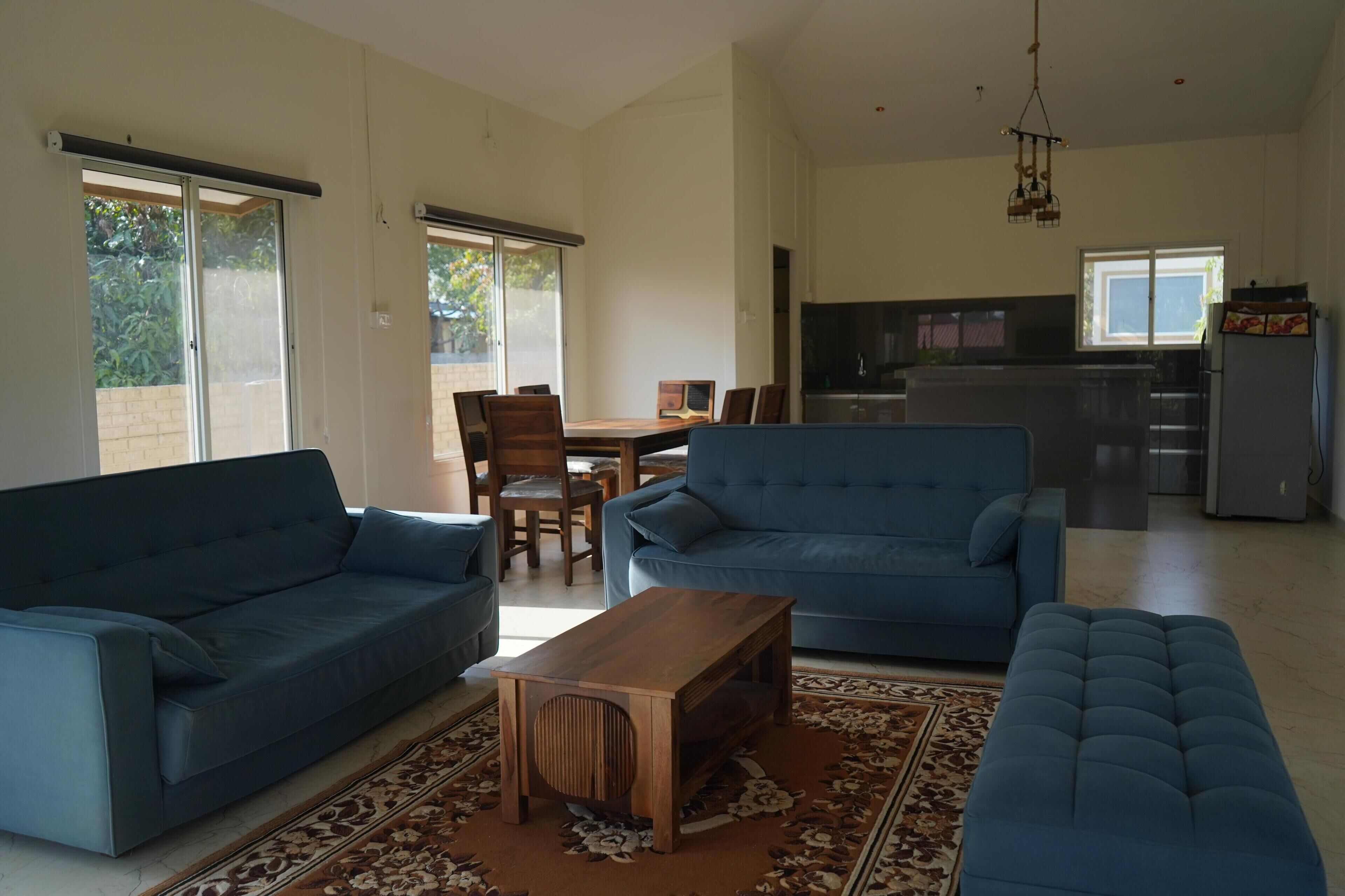 Uma sala de estar ampla com dois sofás azuis, uma mesa de centro de madeira e um tapete estampado.