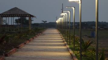 Um caminho pavimentado ladeado por postes de luz e um gazebo.