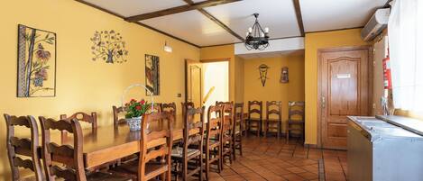 Uma área de refeições com cadeiras de madeira e uma mesa, um candelabro e piso de azulejos.