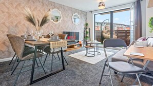 Uma sala de estar moderna com área de jantar, janelas amplas e vista para edifícios.